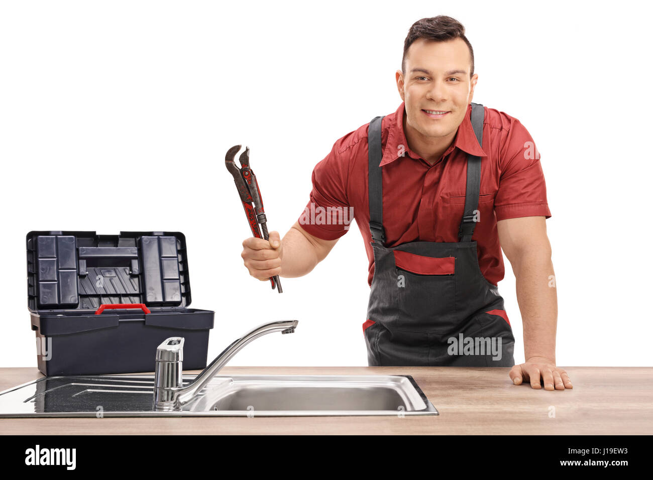 Plumber with a pipe wrench and a toolbox standing behind a sink and ...