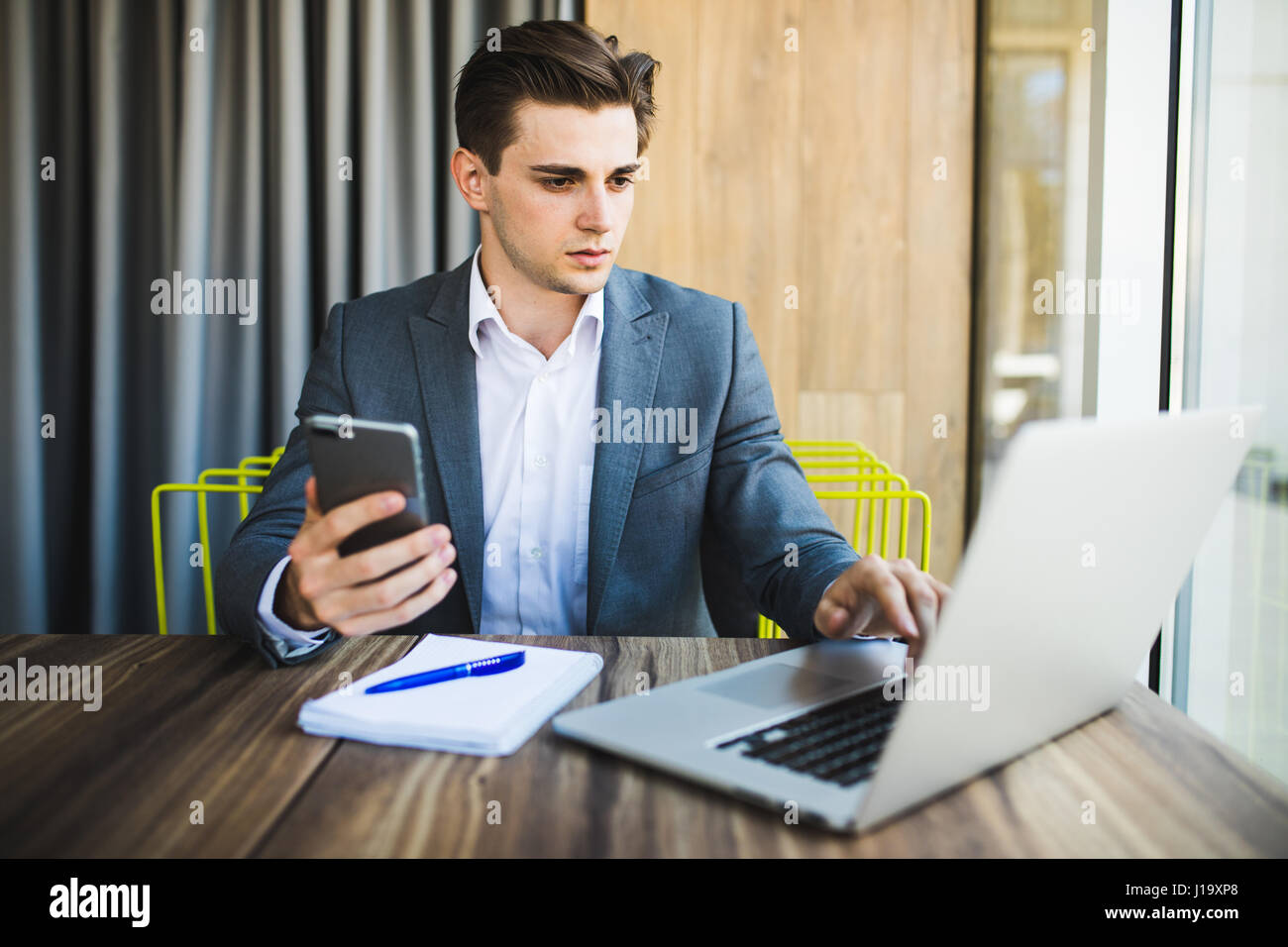 Young happy businessman smiling while reading his smartphone. Portrait ...