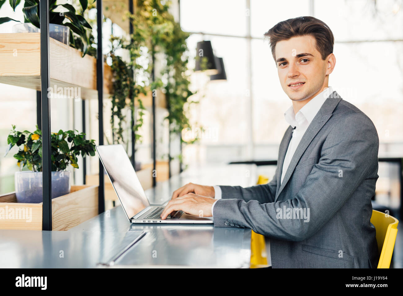 Side view of Smiling business man sitting by the table with laptop ...