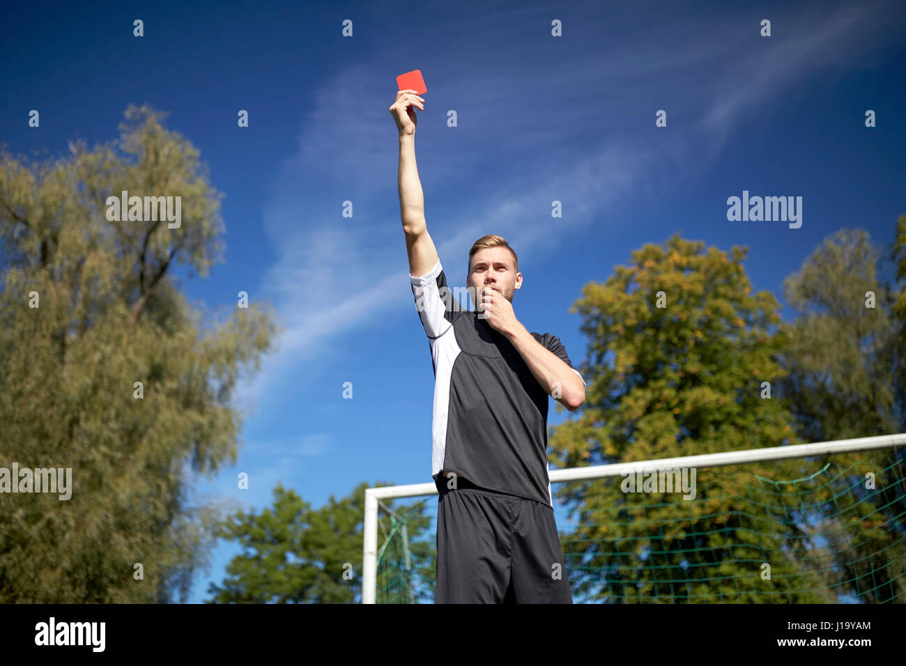 referee on football field showing yellow card Stock Photo - Alamy