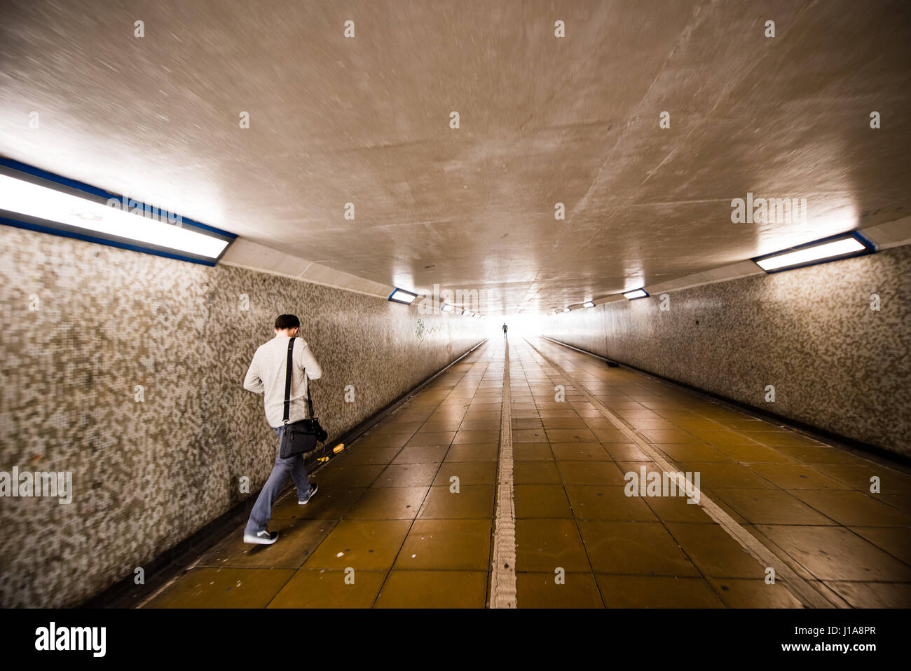 Male white student walks alone through a well-lit subway under ...