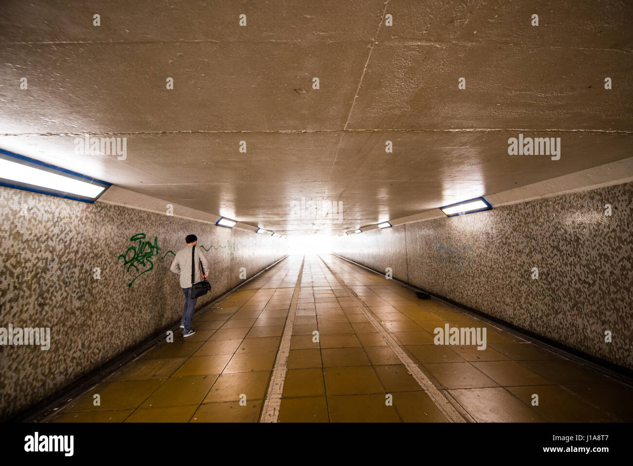 Male white student walks alone through a well-lit subway under ...