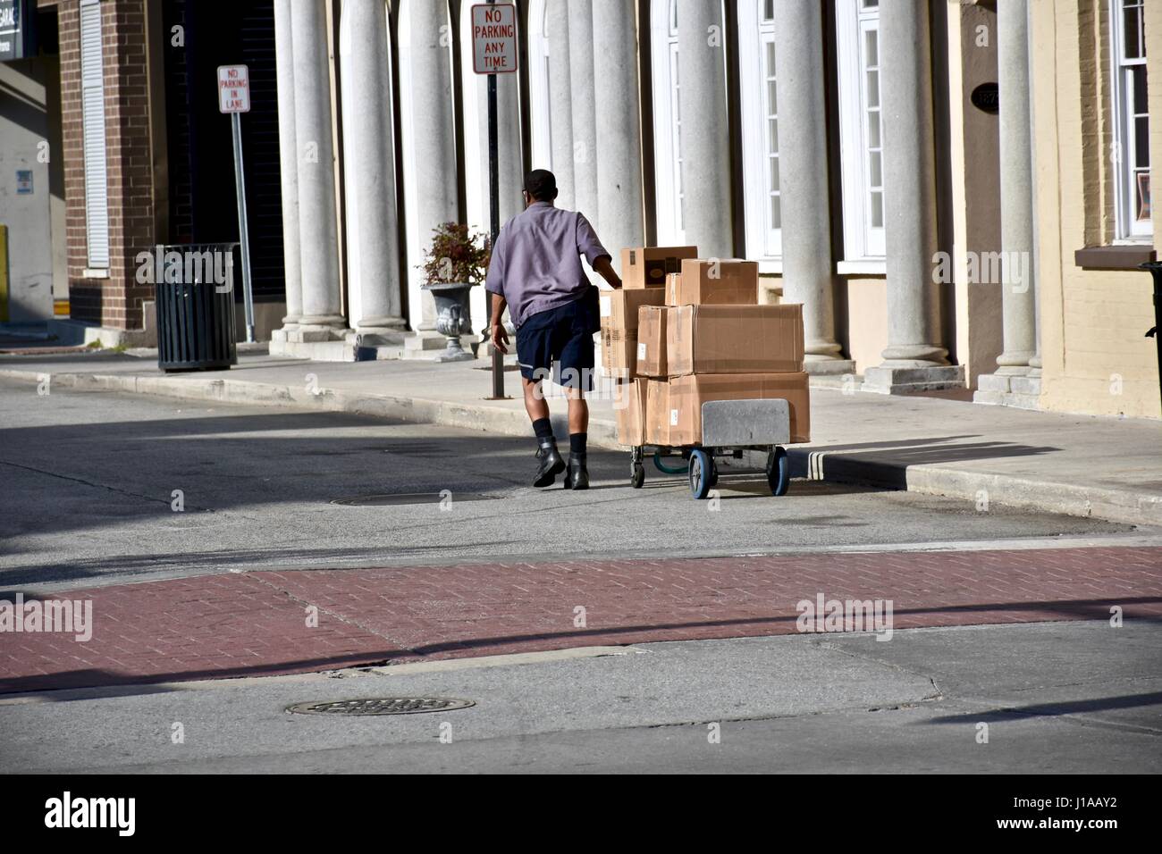 Mail carrier pulling boxes through the city Stock Photo - Alamy