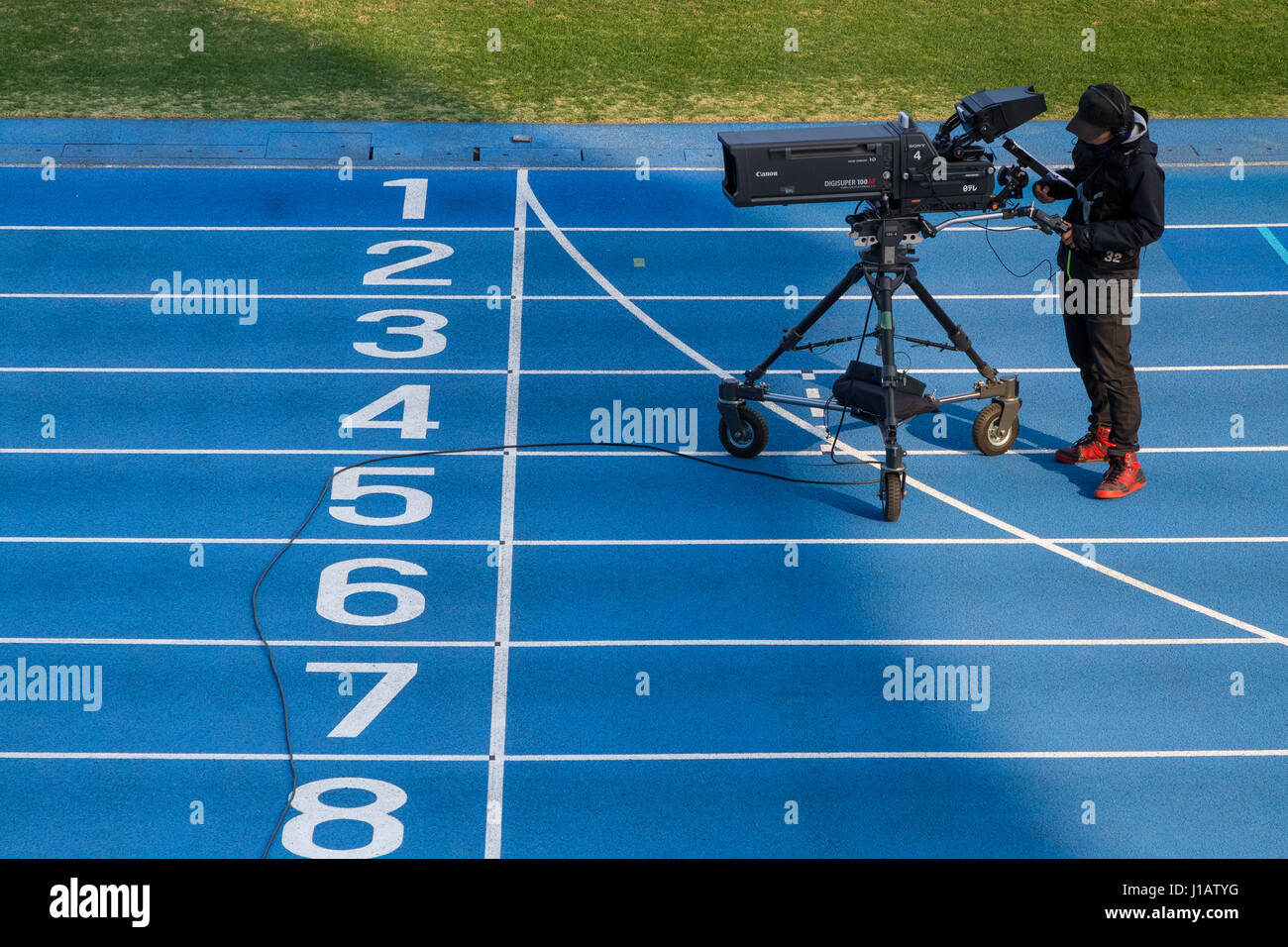 A TV camera and cameraman on a running track in a stadium in Komazawa ...
