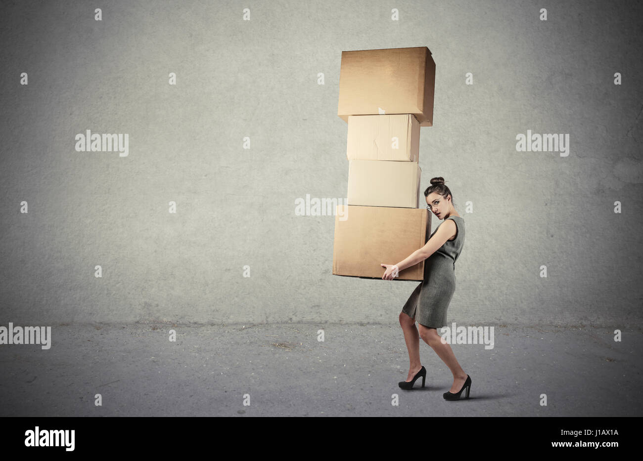 Brunette woman carrying heavy boxes Stock Photo - Alamy