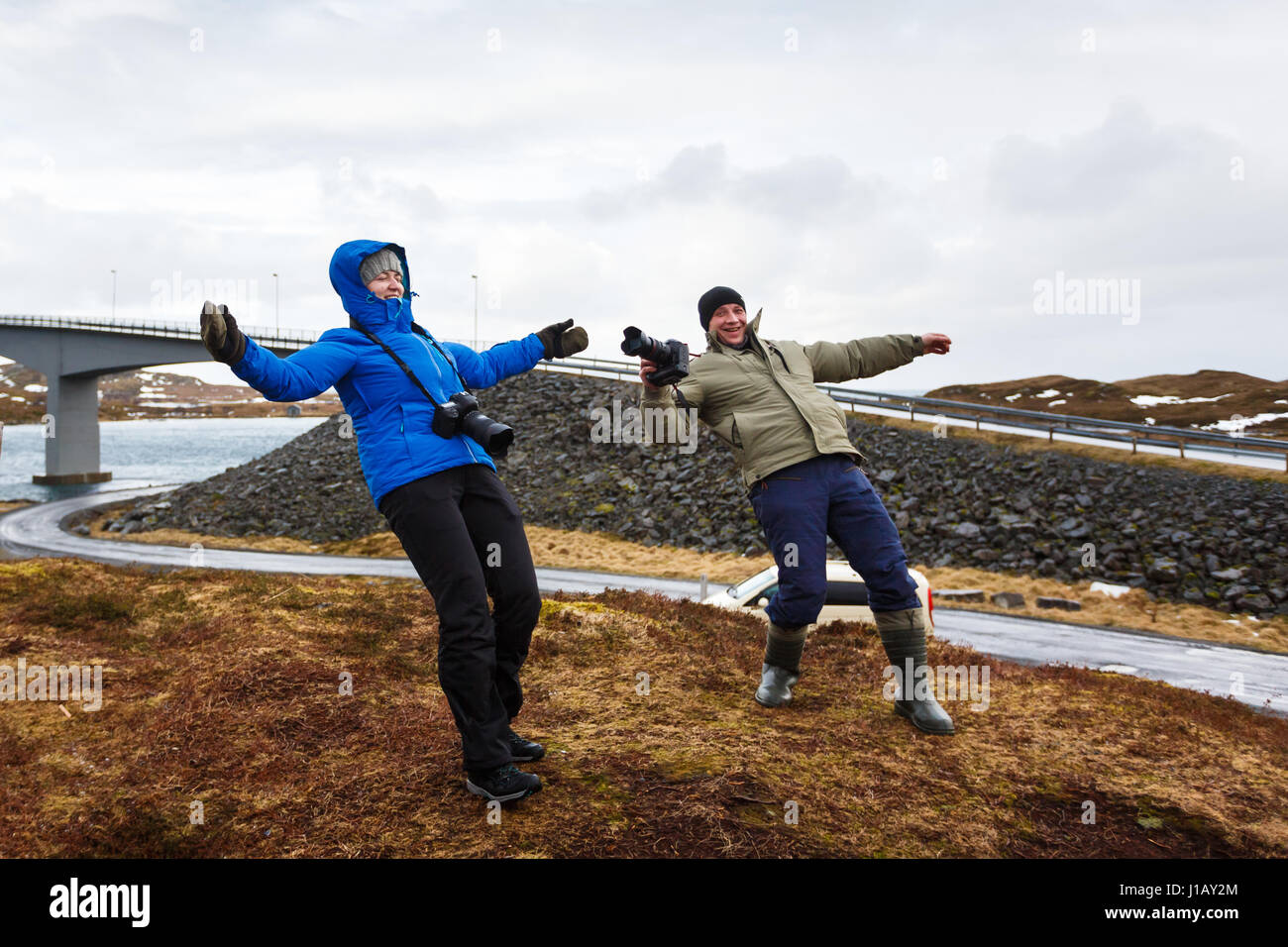 Two photographers bended under a strong gust of wind in Lofoten, winter ...
