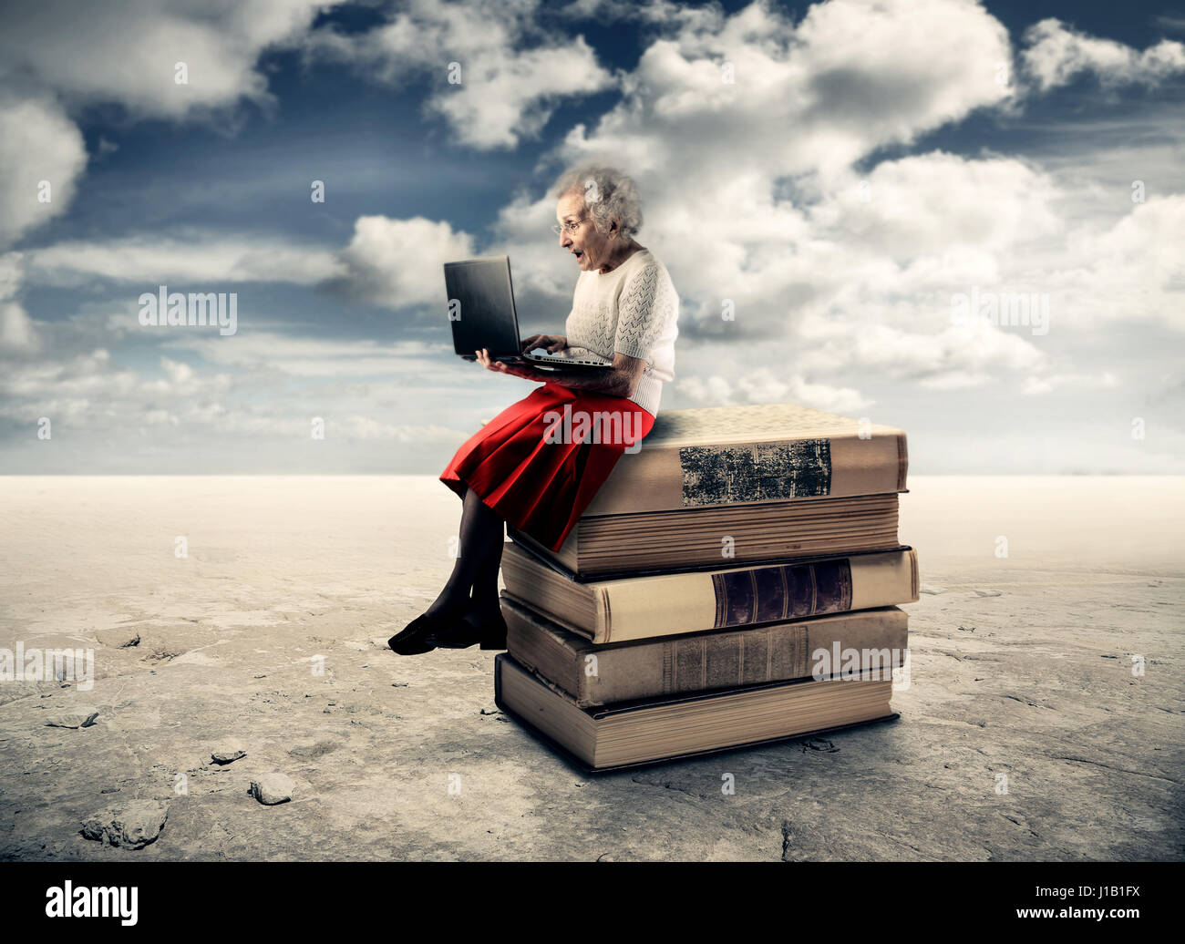 Old lady with laptop sitting on books Stock Photo - Alamy