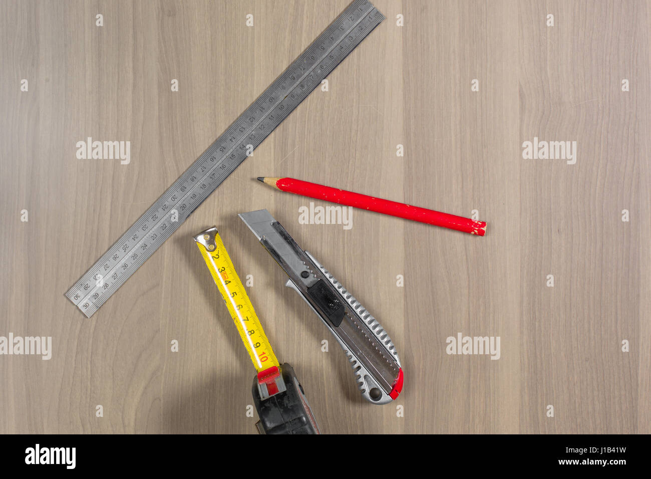 Different tools on a wooden background. Ruler, pencil, knife, roulette ...