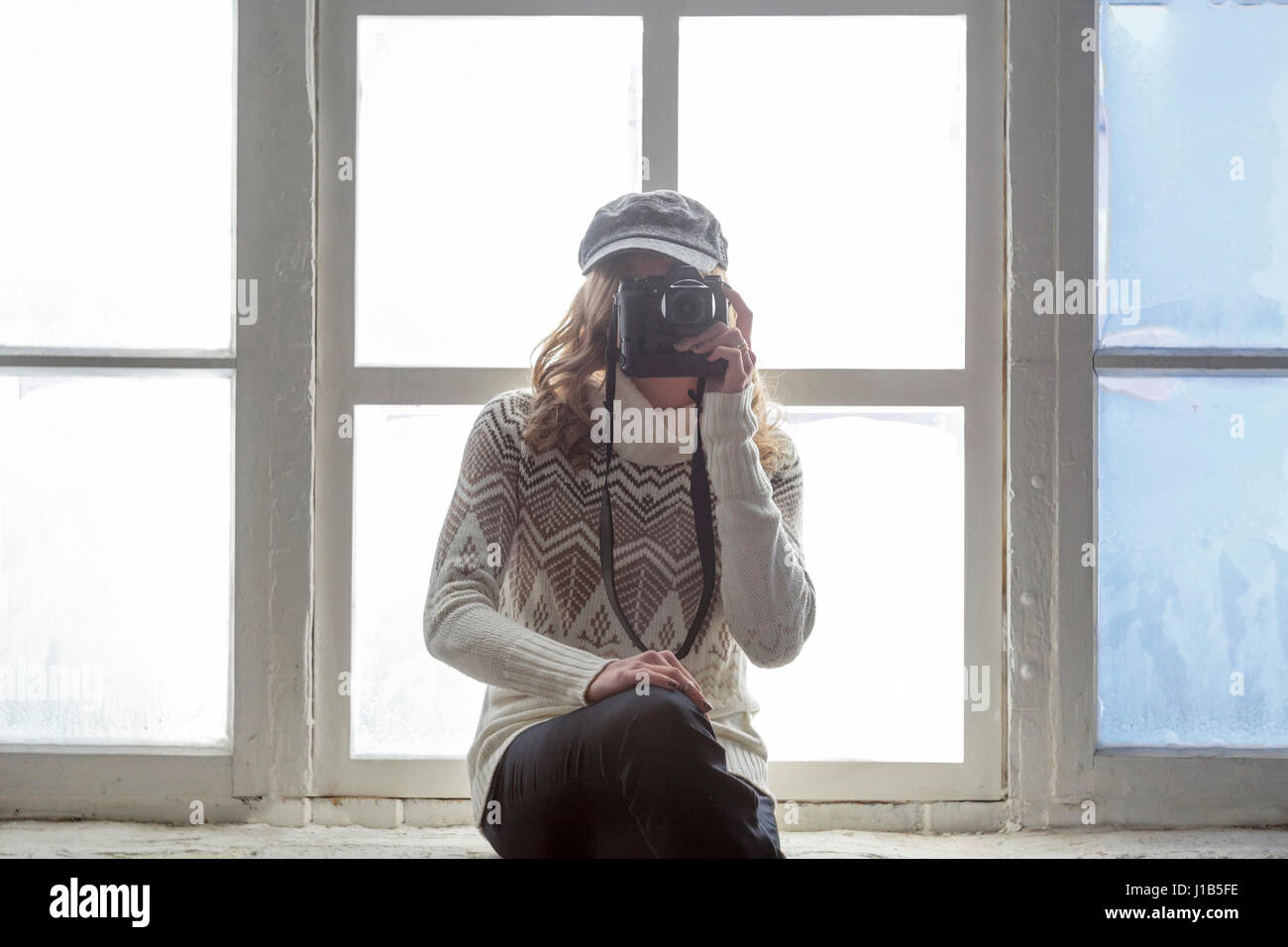Caucasian woman on window sill photographing with camera Stock Photo ...