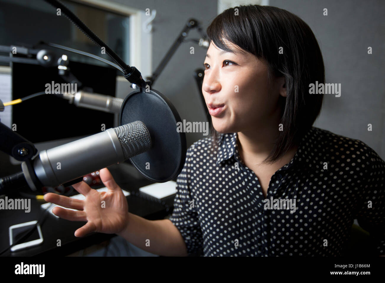Asian woman talking into microphone Stock Photo - Alamy