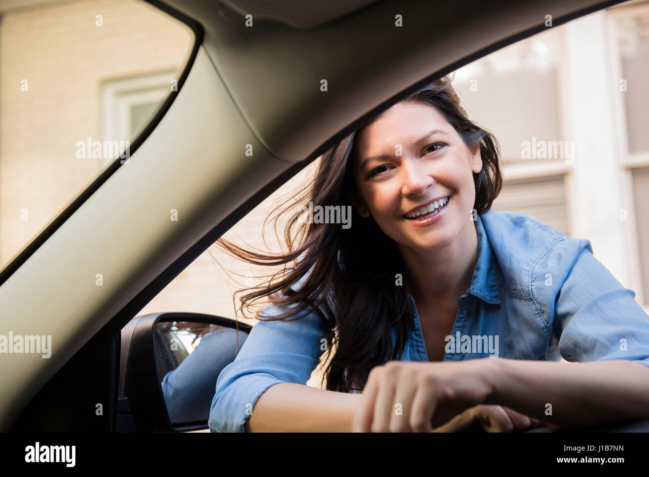 Smiling Caucasian woman leaning in car window Stock Photo - Alamy