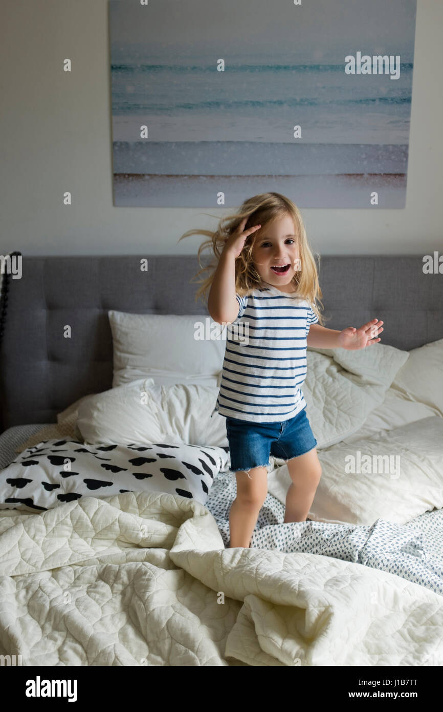 Caucasian girl jumping on bed Stock Photo - Alamy