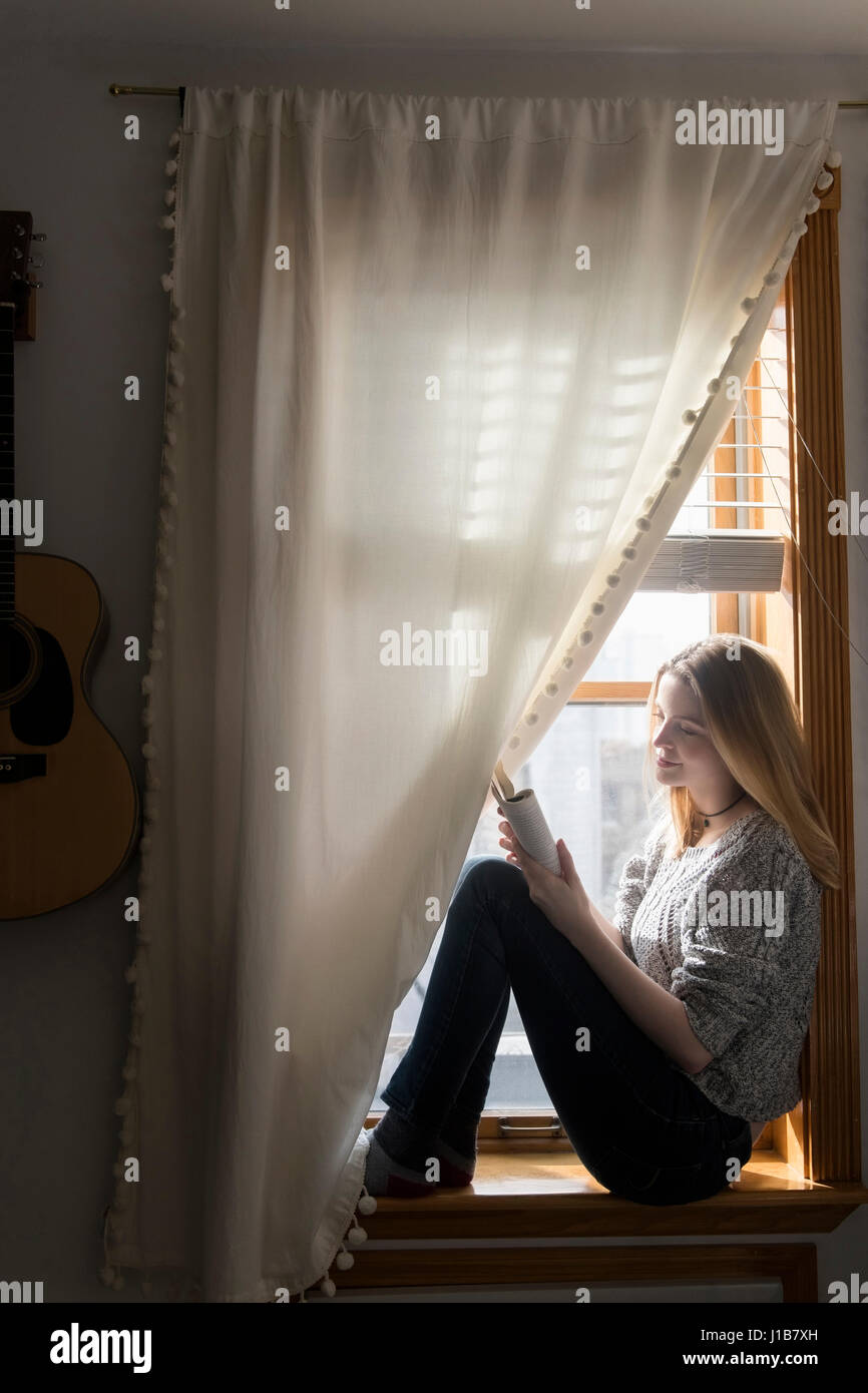 Smiling woman sitting in window using digital tablet Stock Photo - Alamy