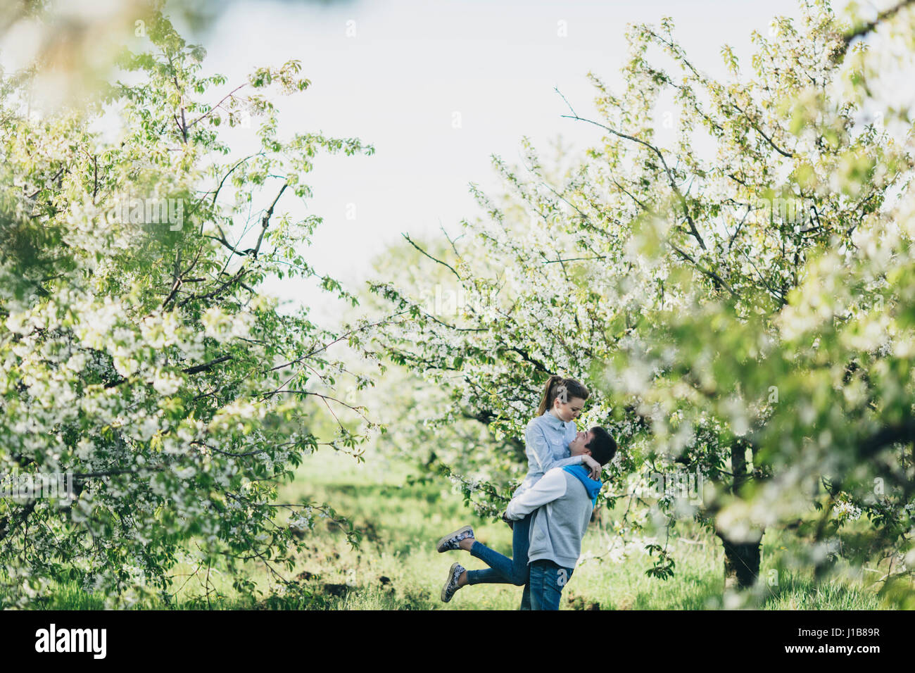 Caucasian man lifting woman under flowering trees Stock Photo - Alamy