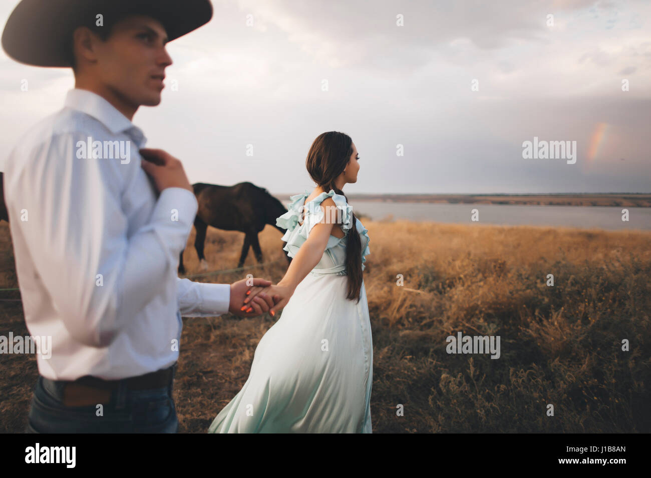 Caucasian woman holding hands with cowboy near river Stock Photo - Alamy