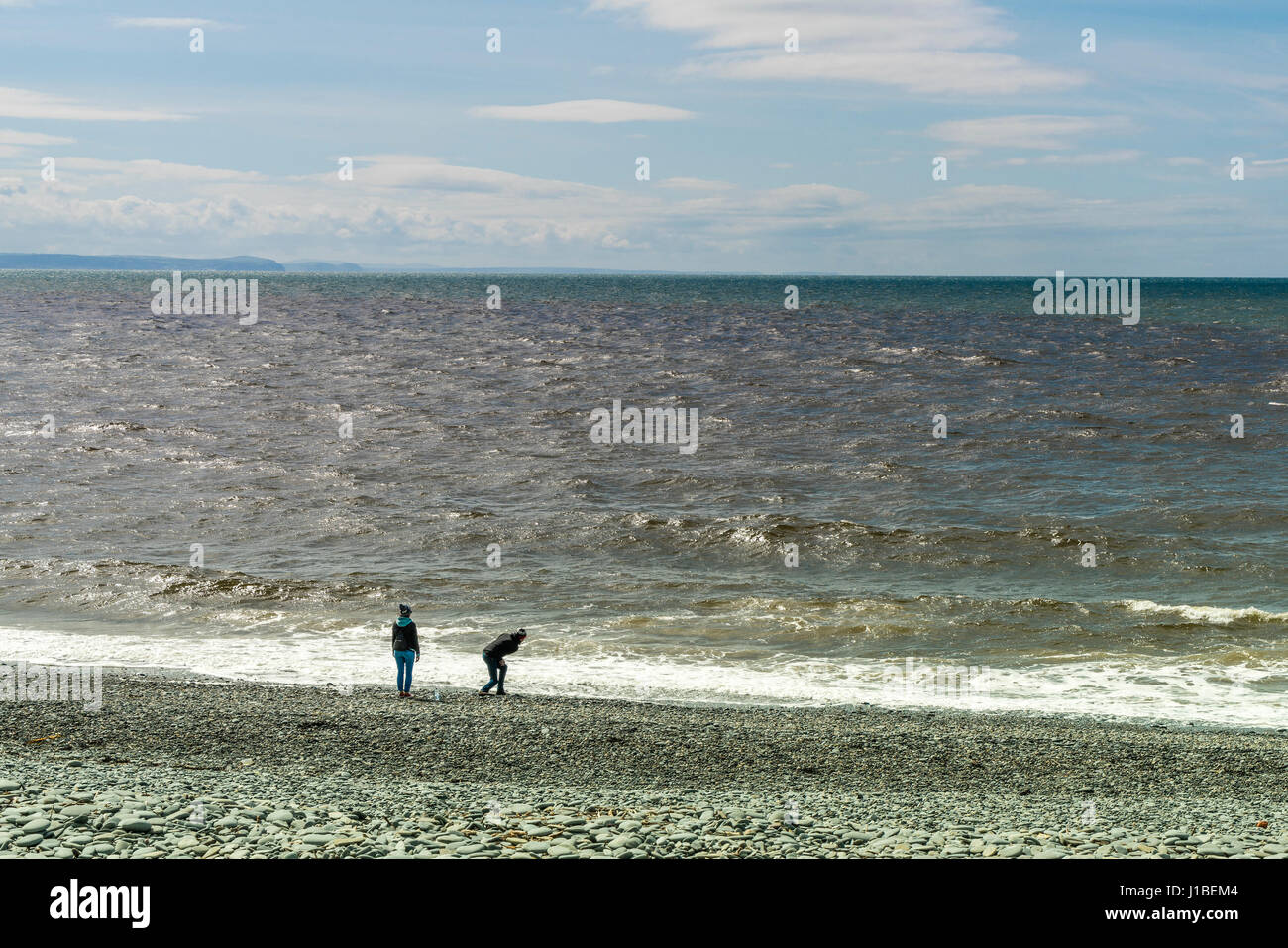 Two teenage boys playing and skimming pebbles on the beach in ...