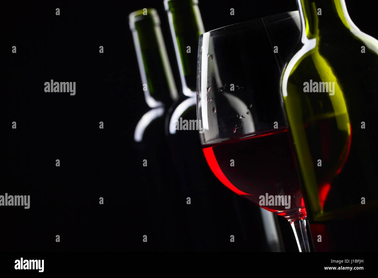 Bottles and glass of red wine on a black background . Selective focus ...