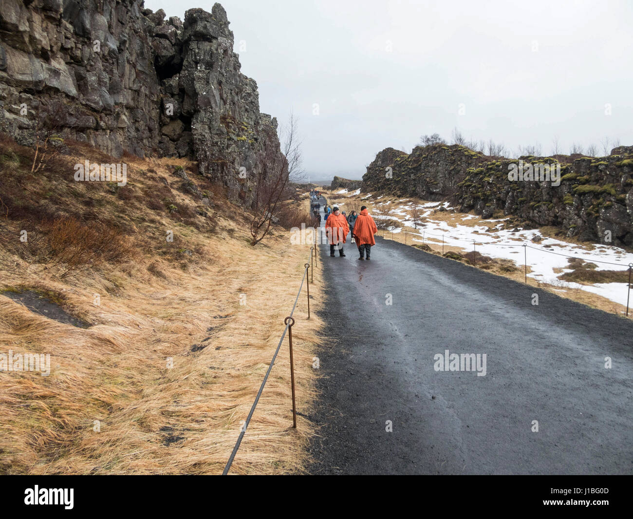 Tourists walk through Almannagja gorge, situated in Thingvellir ...