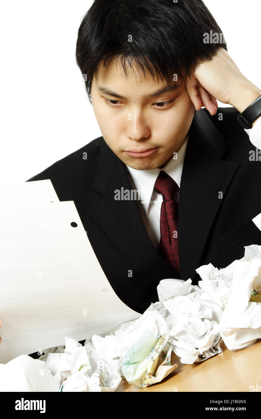 A stressed out businessman with crumpled paper all over table Stock ...