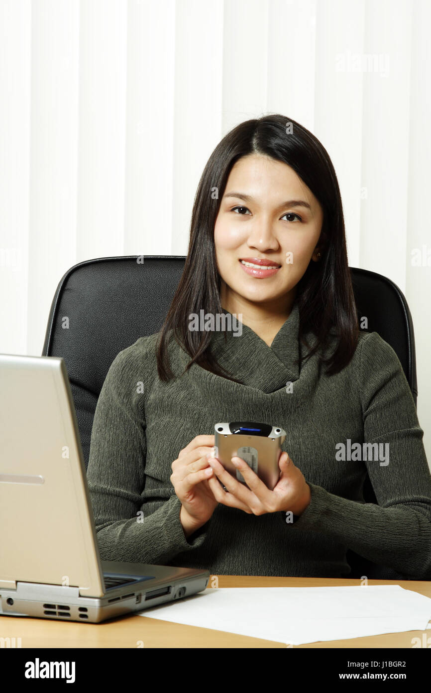 A busy businesswoman working on her PDA and laptop Stock Photo - Alamy