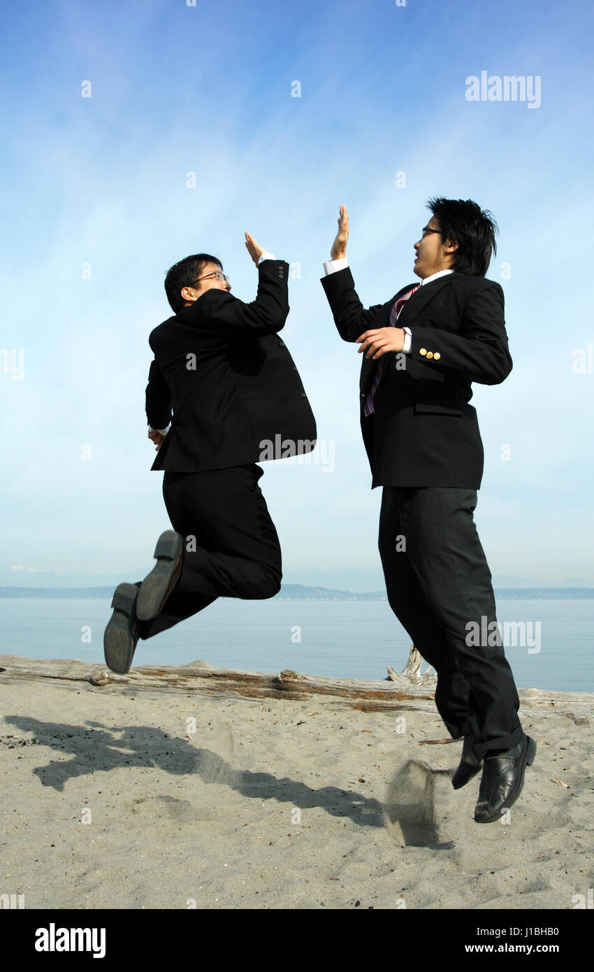 Two businessmen jumping happily on the beach Stock Photo - Alamy