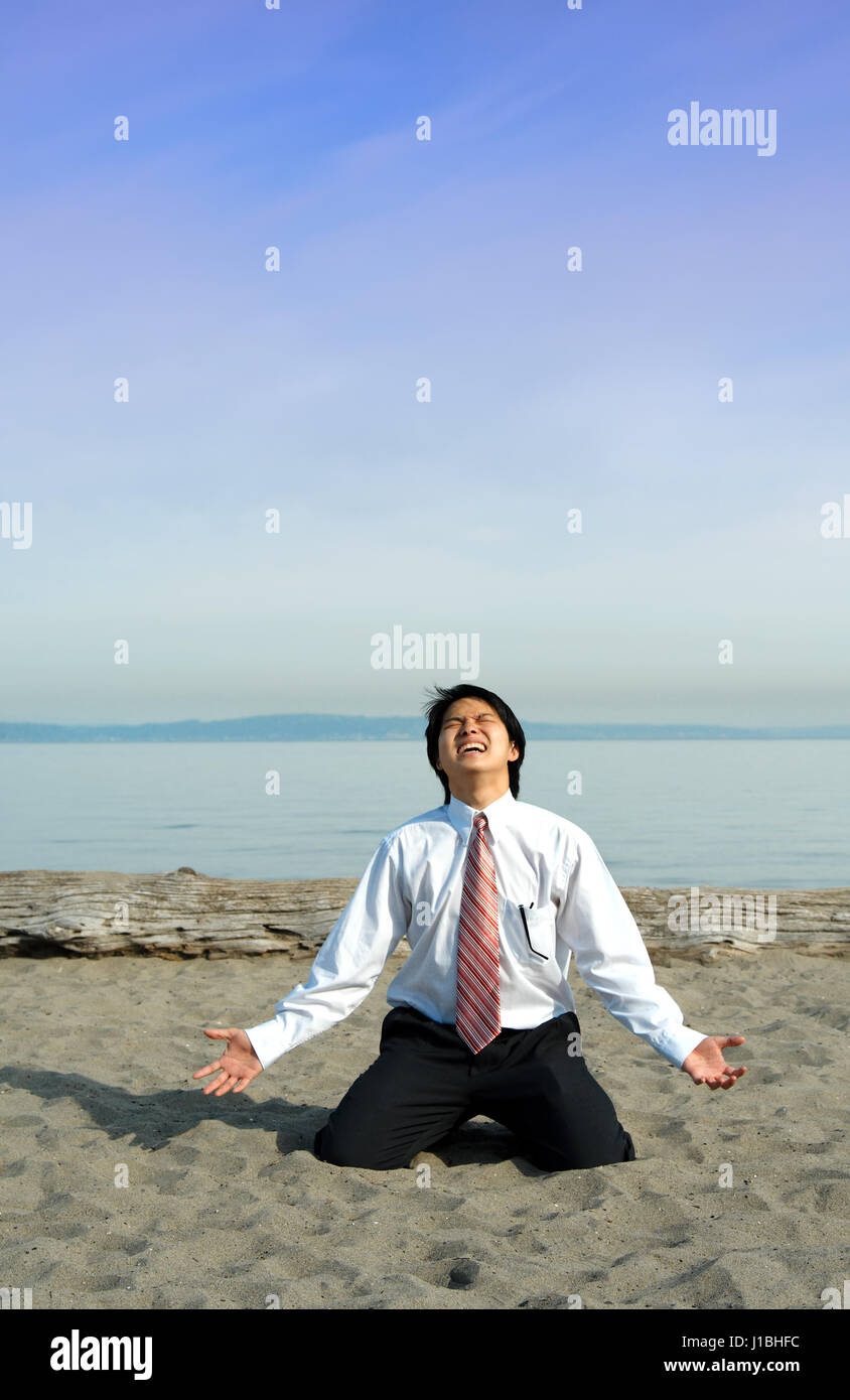Stressed businessman screaming and kneeling on the beach Stock Photo ...