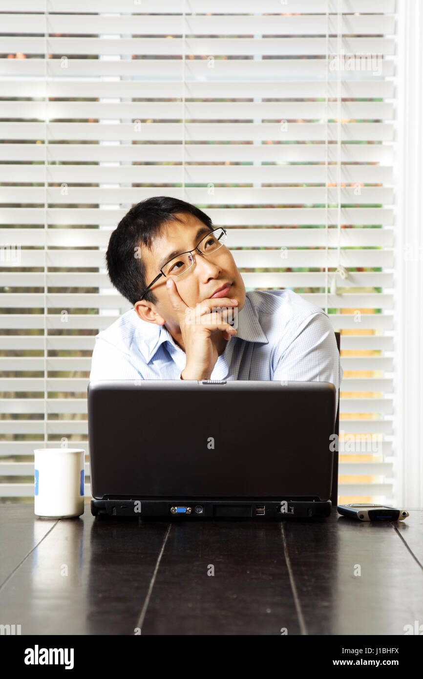 An asian businessman thinking and working on his laptop Stock Photo - Alamy