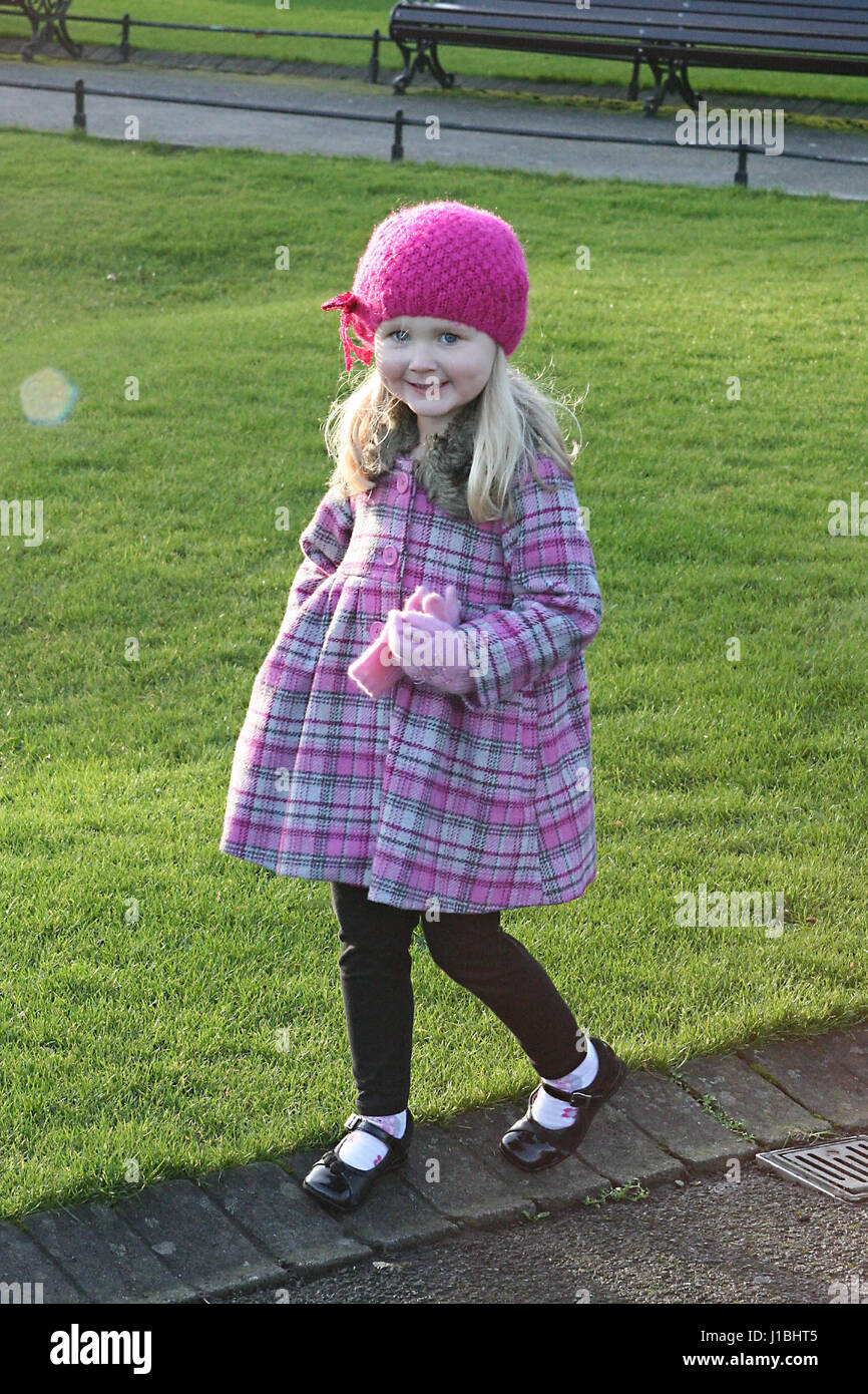 little girl child wearing a pink wolly hat and warm pollen co running ...