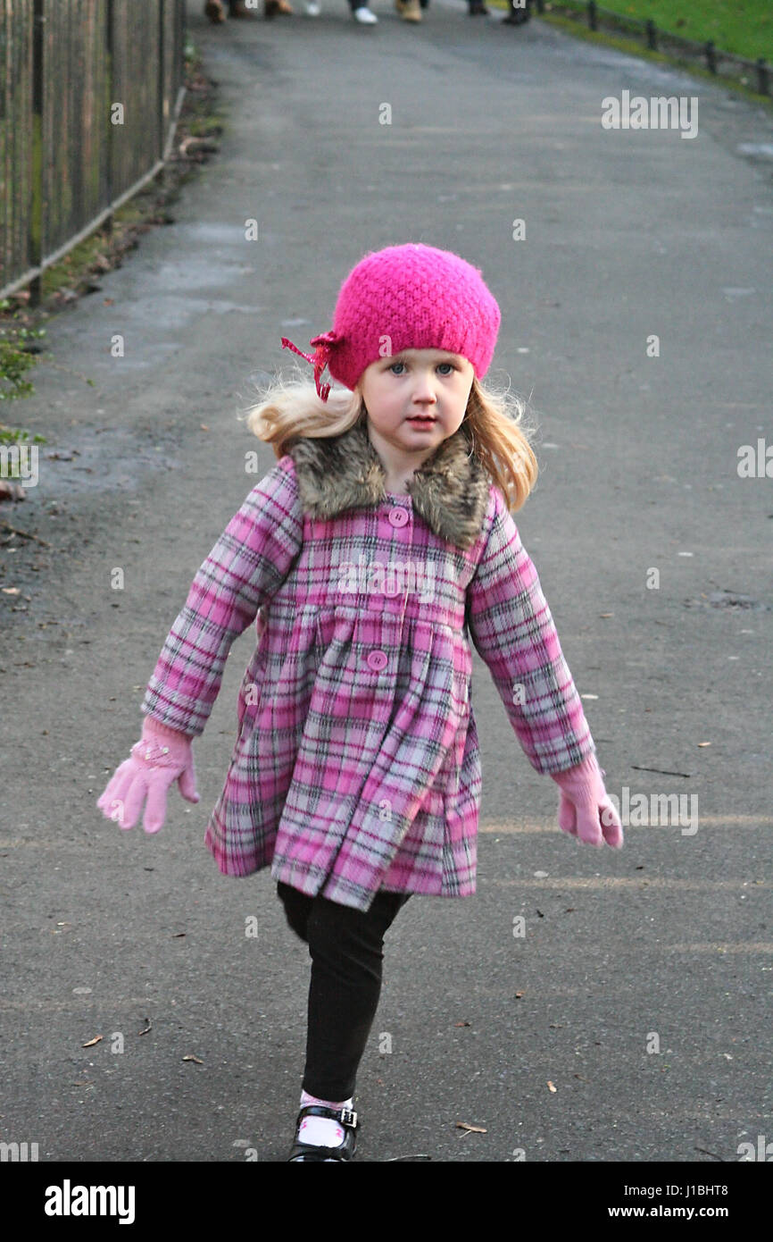 little girl child wearing a pink wolly hat and warm pollen co running ...