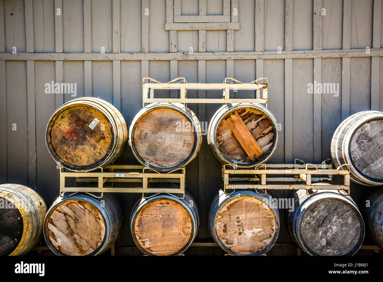 A stack and row of aged oak wood cask barrels for wine storage outdoors ...