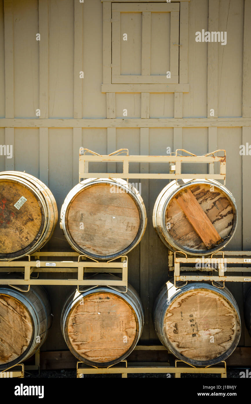 A stack and row of aged oak wood cask barrels for wine storage outdoors ...