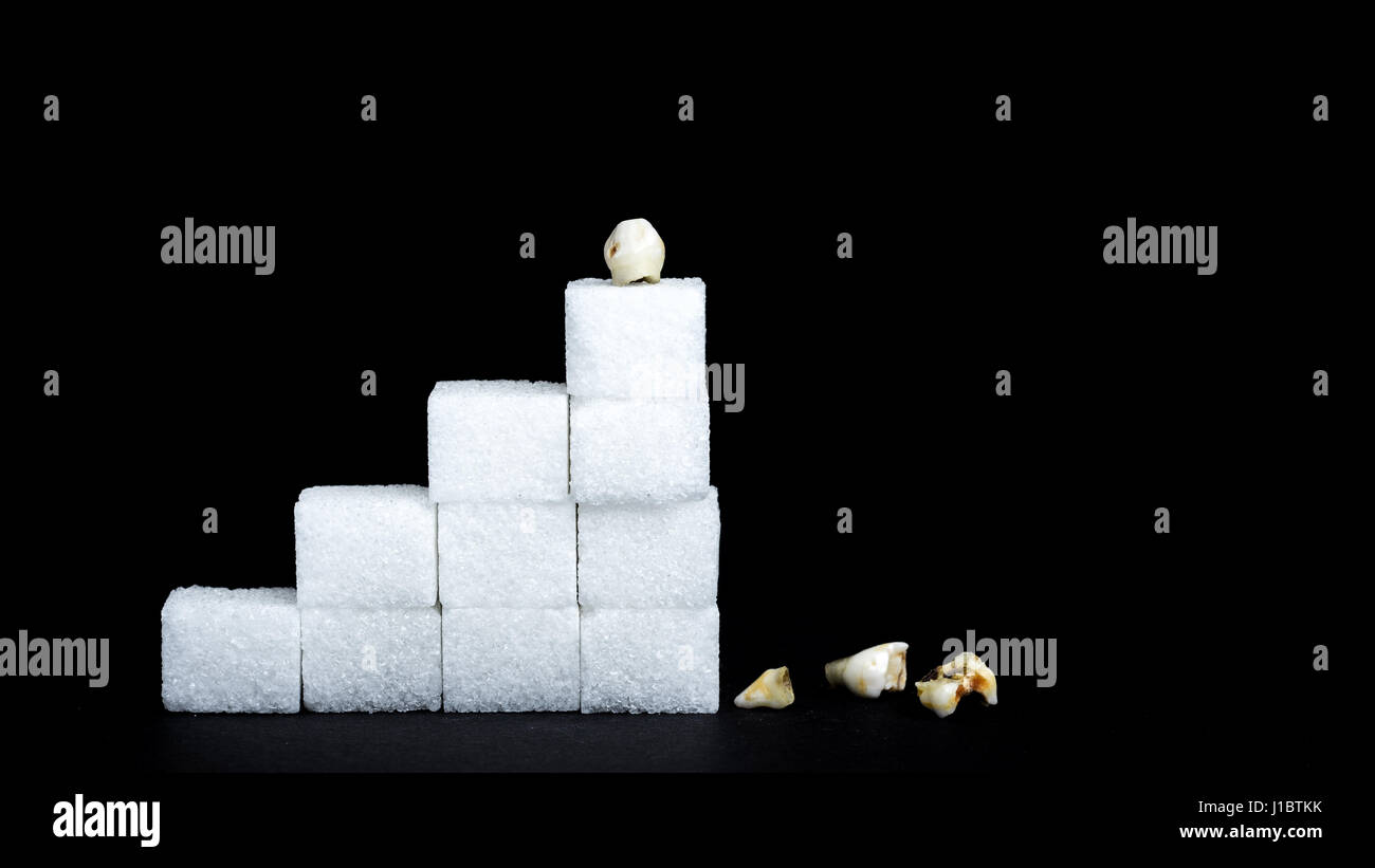 Decayed teeth and sugar cubes in front of black background - Concept of ...