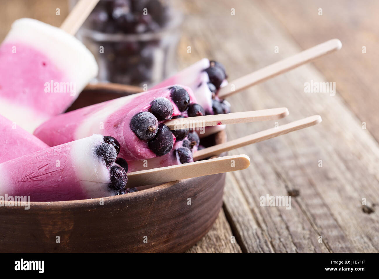Homemade berry yogurt ice pops decorated with frozen blackcurrant in ...