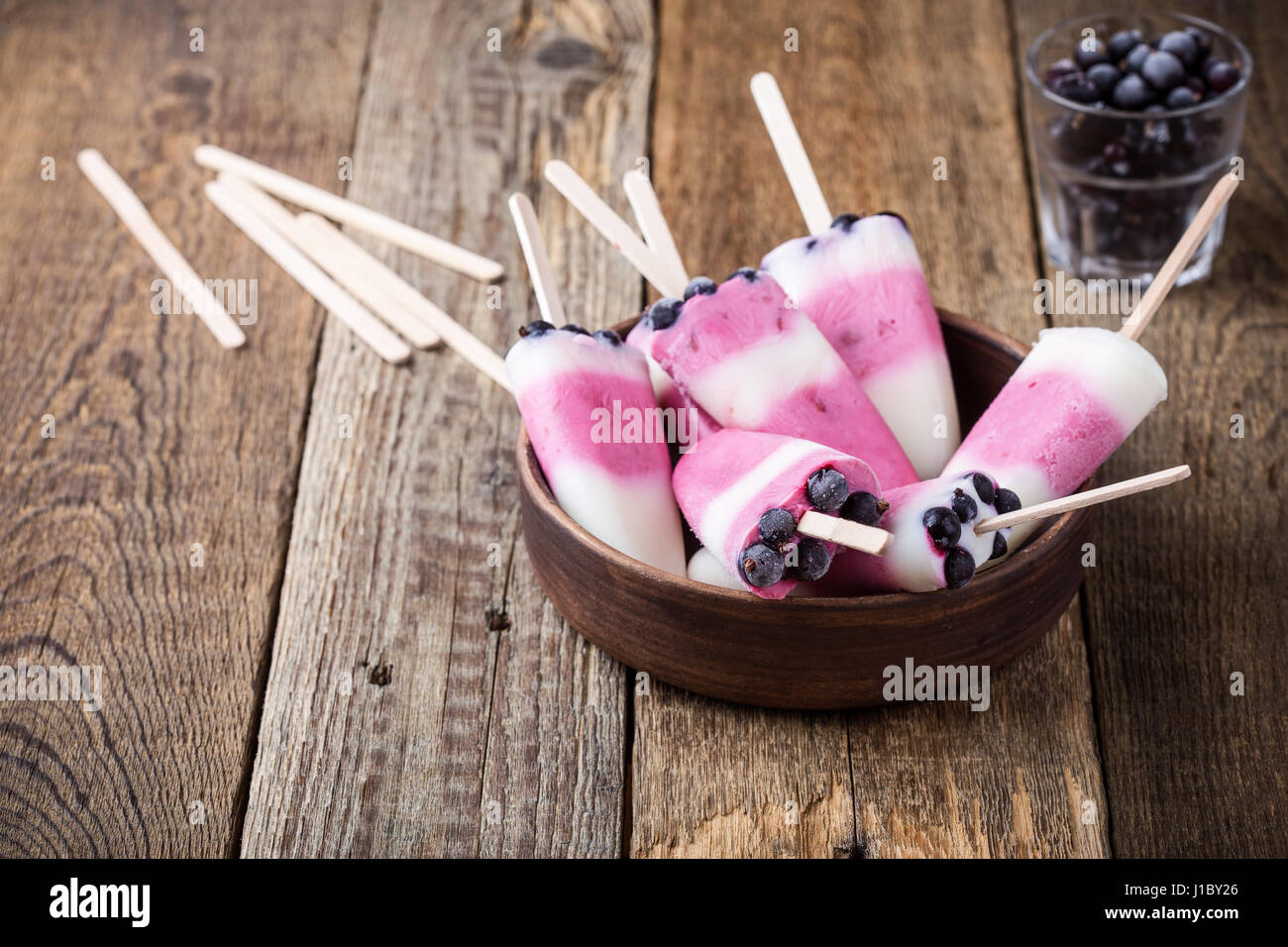 Homemade berry yogurt ice pops decorated with frozen blackcurrant in ...