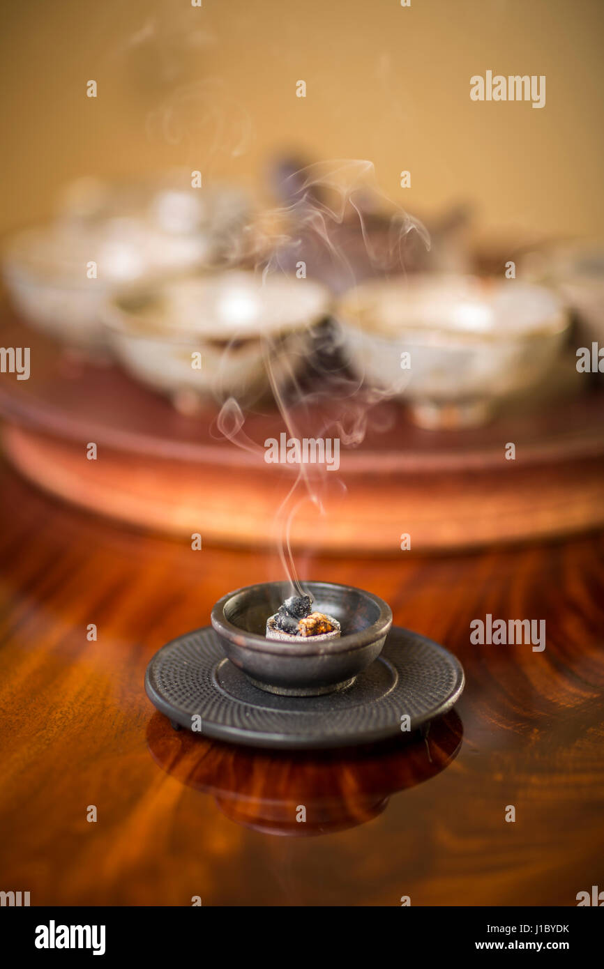 Incense burning in front of ceramic tea cups on a tray Stock Photo - Alamy