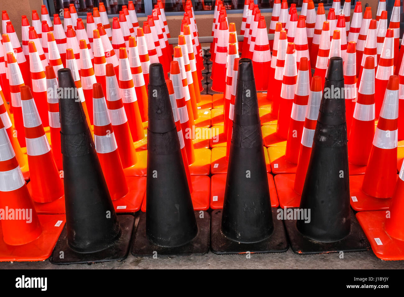 Four Black Traffic Cones In Front of a Vast Array of Bright Orange And ...
