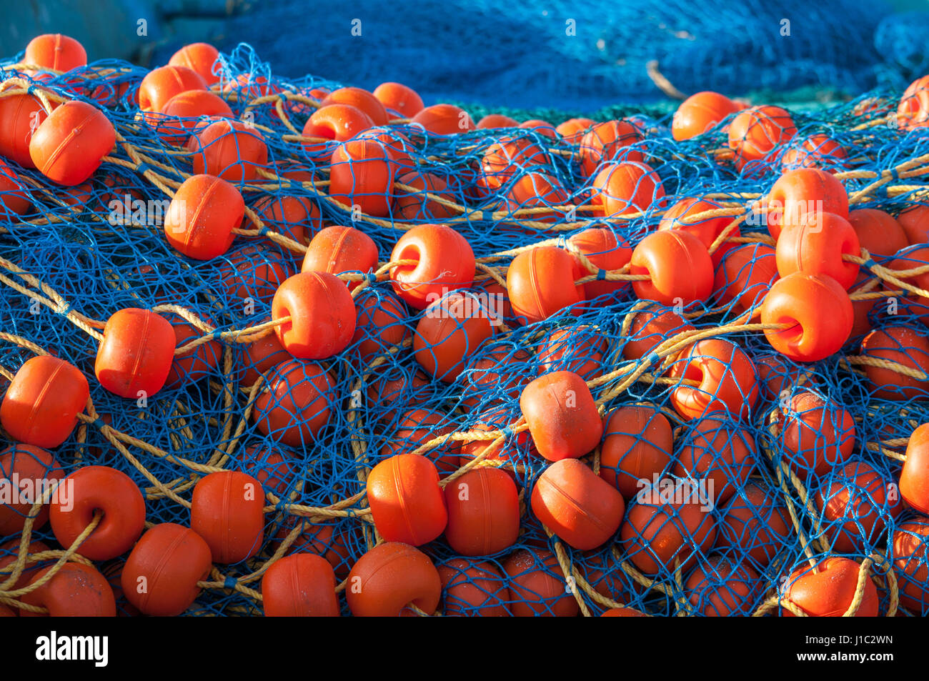 Bright blue fishing net with orange floats closeup Stock Photo - Alamy