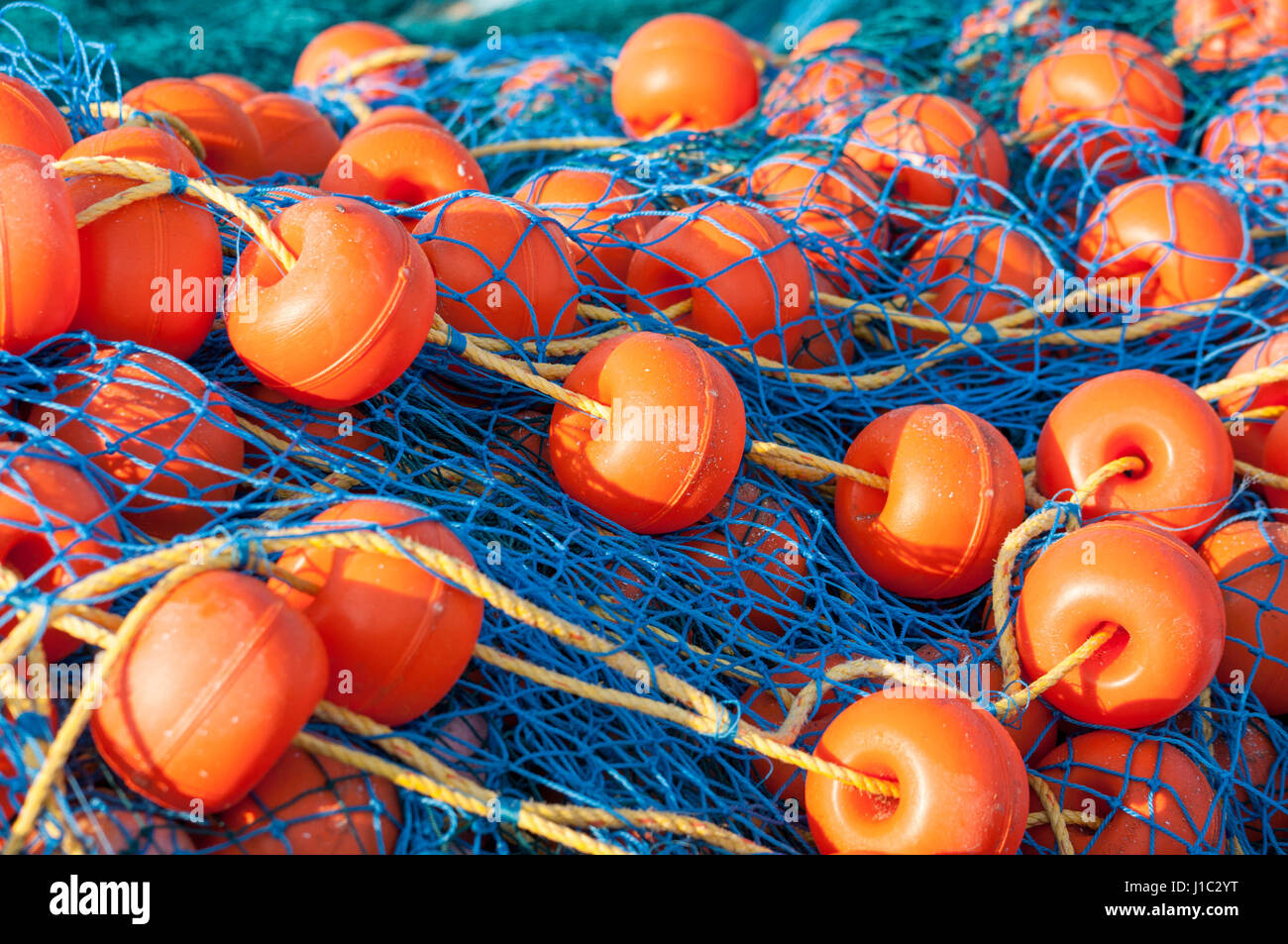 Bright blue fishing net with orange floats closeup Stock Photo - Alamy