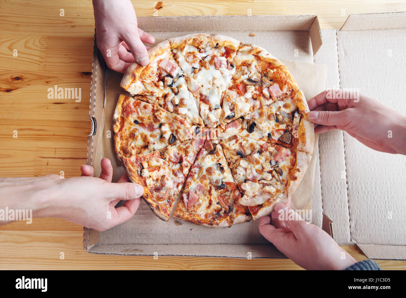 A group of people taking slices of pizza out of the box. fast delivery ...