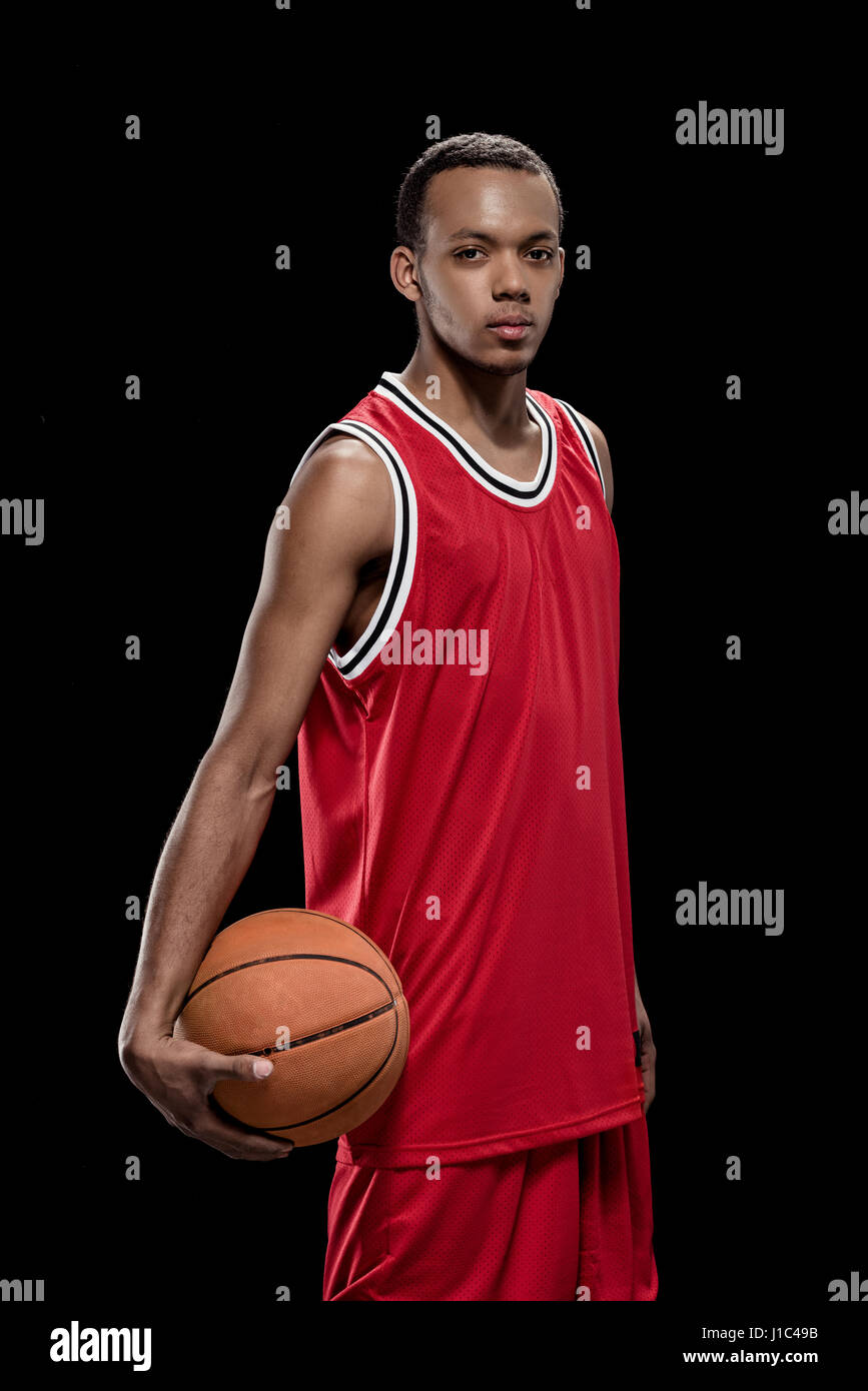 Young confident basketball player standing with ball and looking at ...