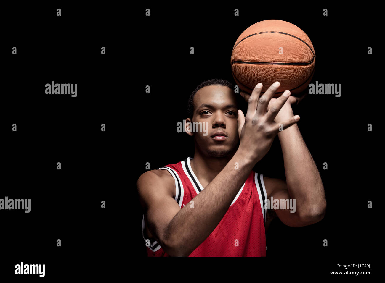 Young athletic man in uniform playing basketball with ball on black ...