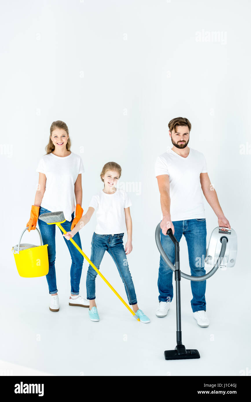 parents and little daughter with different cleaning supplies on white ...