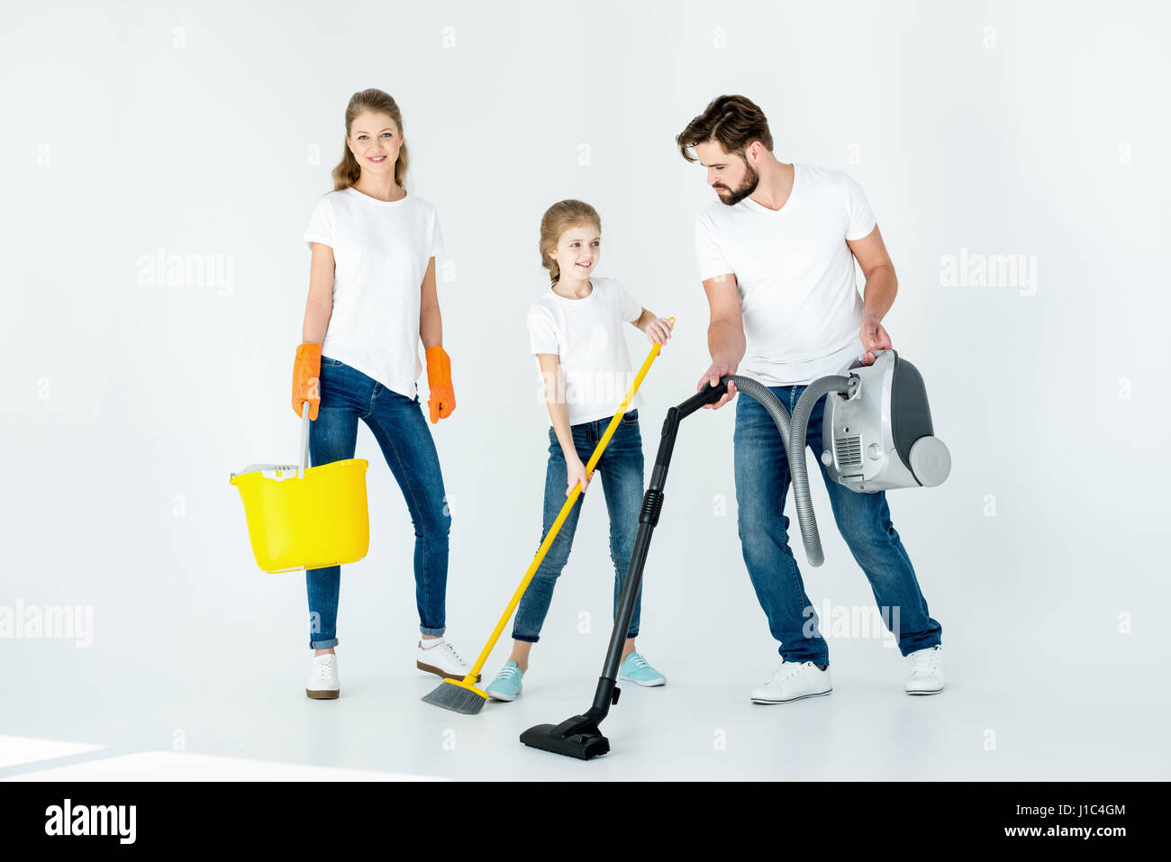parents and little daughter with different cleaning supplies on white ...