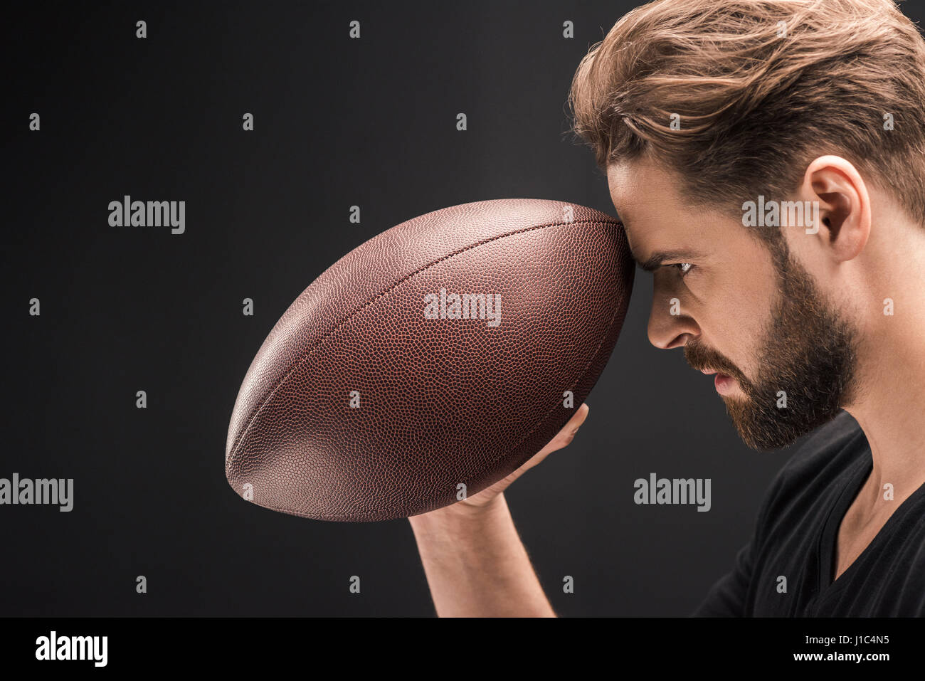 side view of angry bearded man holding rugby ball on black Stock Photo ...