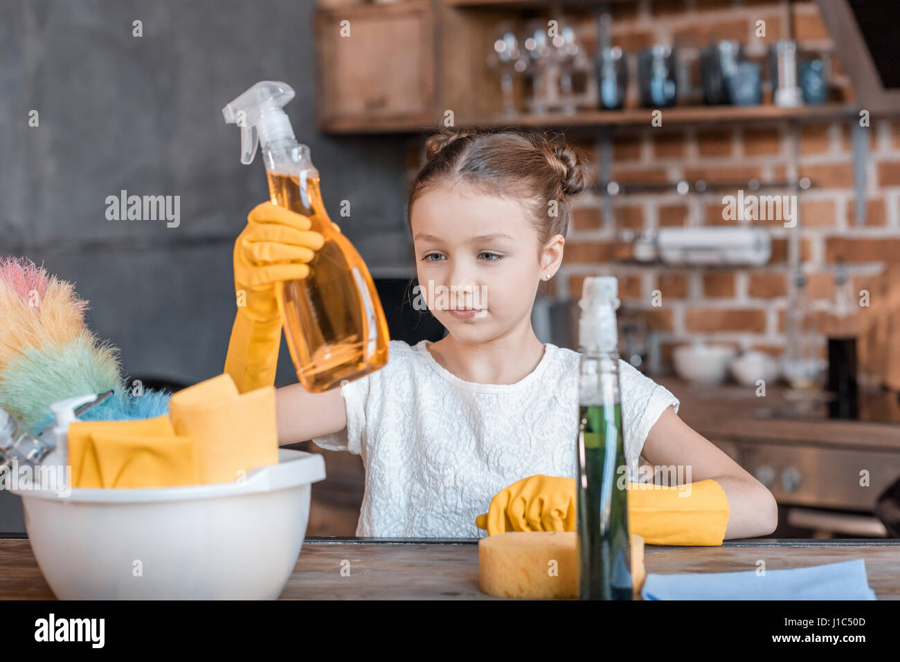 Adorable girl with spray bottles and different cleaning supplies at ...