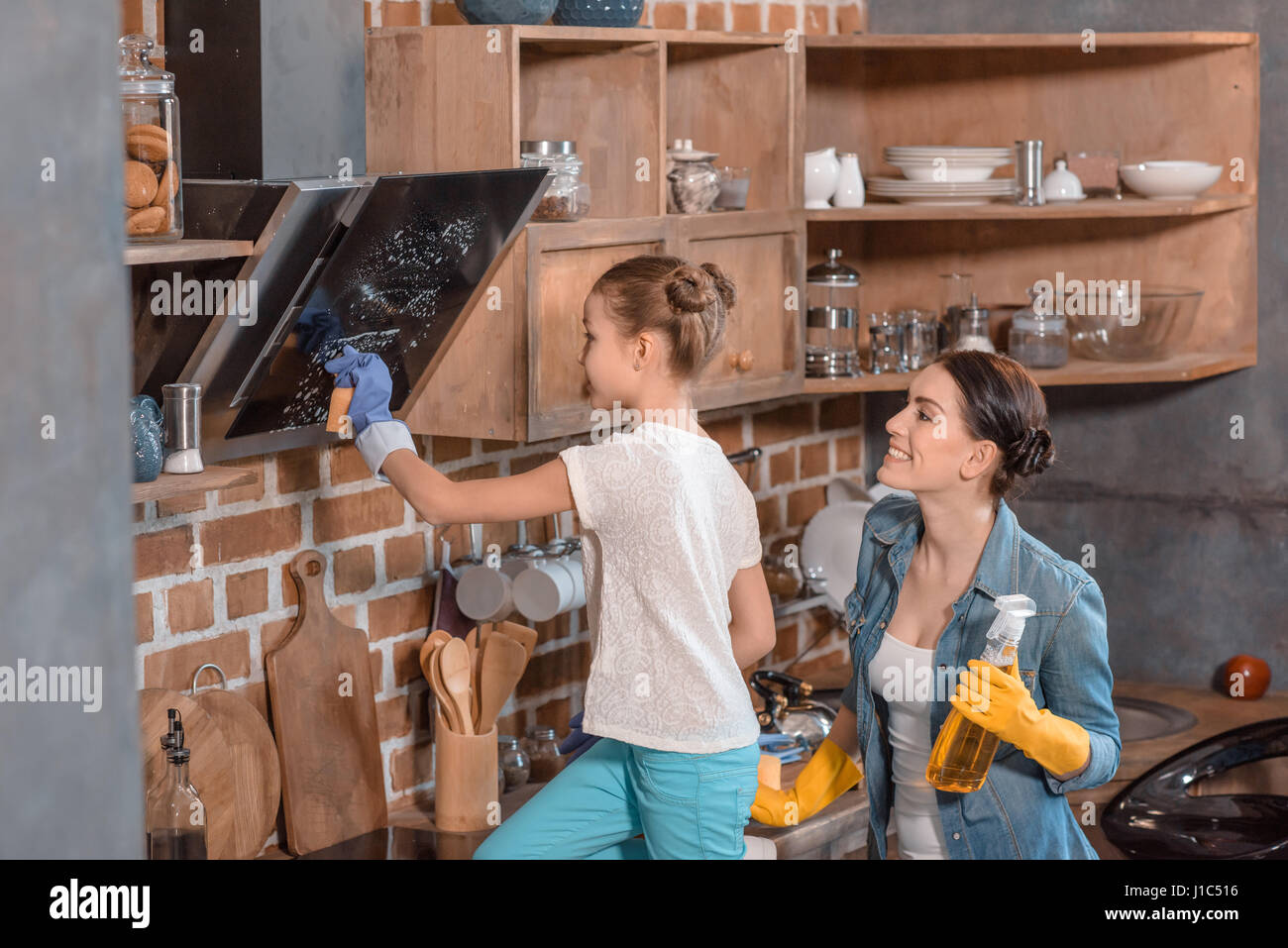 side view of daughter helping mother cleaning tv set at home Stock ...