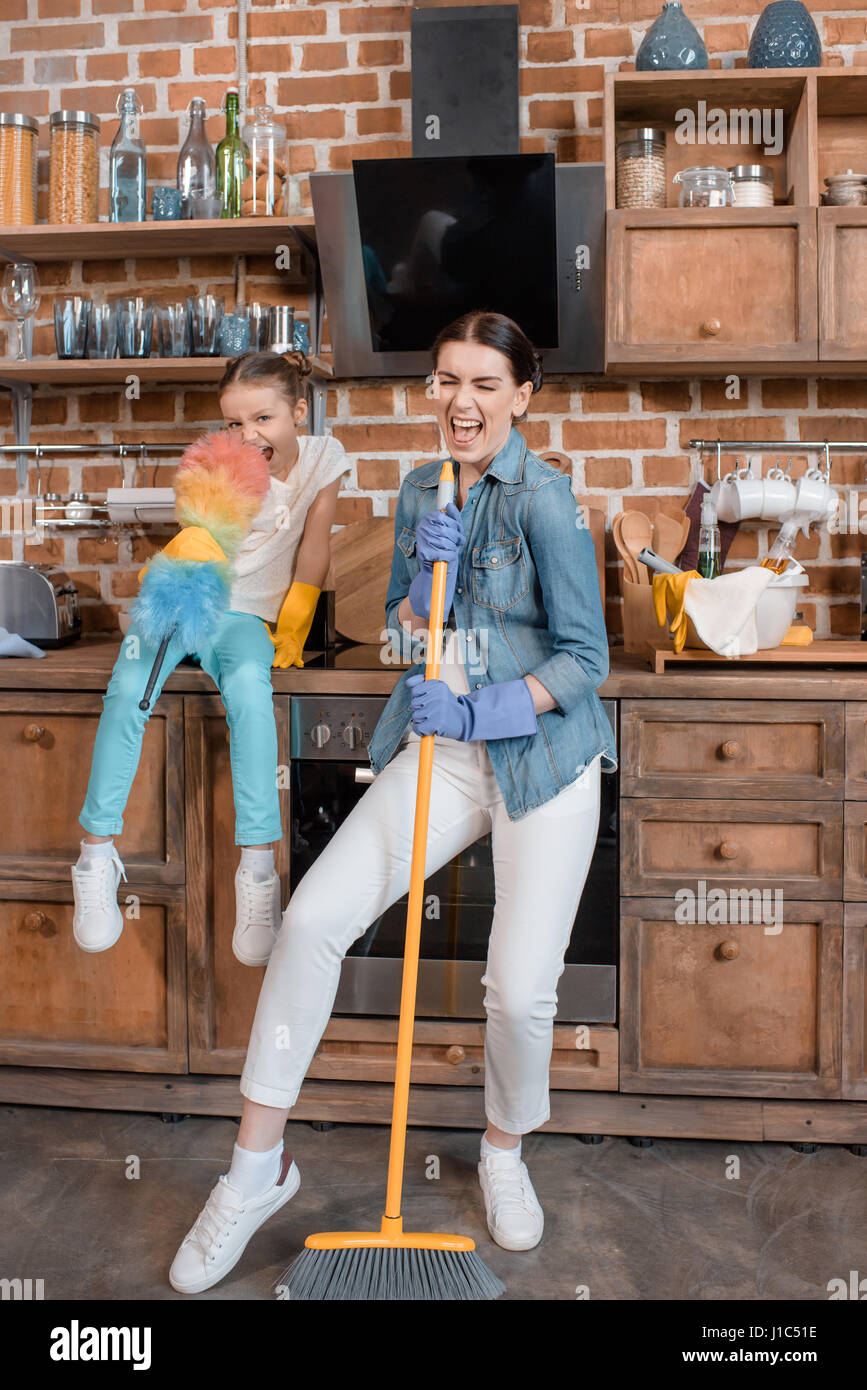 Happy mother and daughter with duster and broom having fun while ...