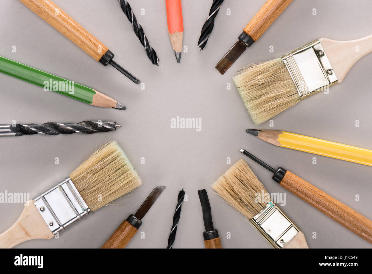 top view of various paint brushes, pencils, chisels and drills on grey ...
