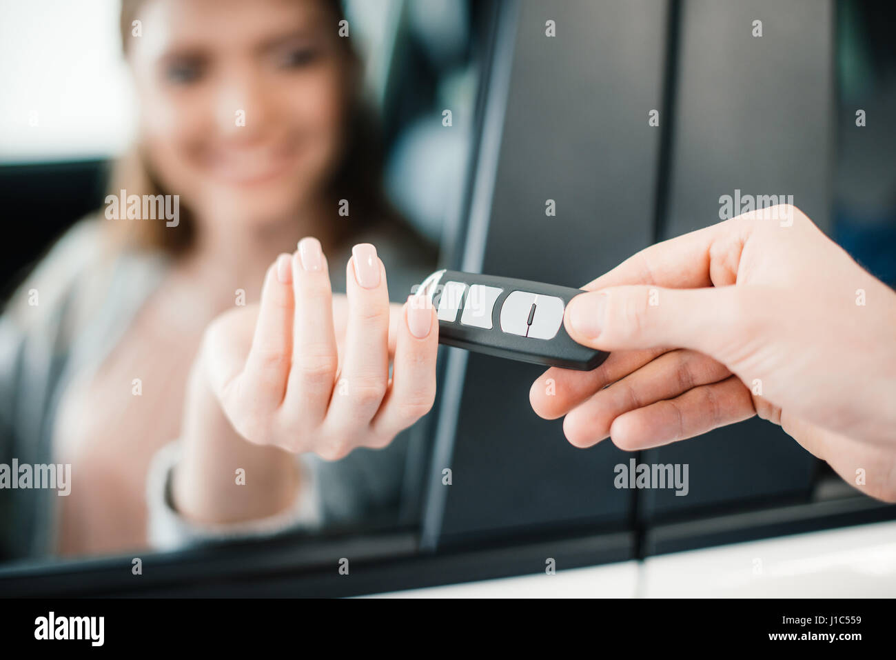 Person giving car key to woman sitting in car in dealership salon Stock ...