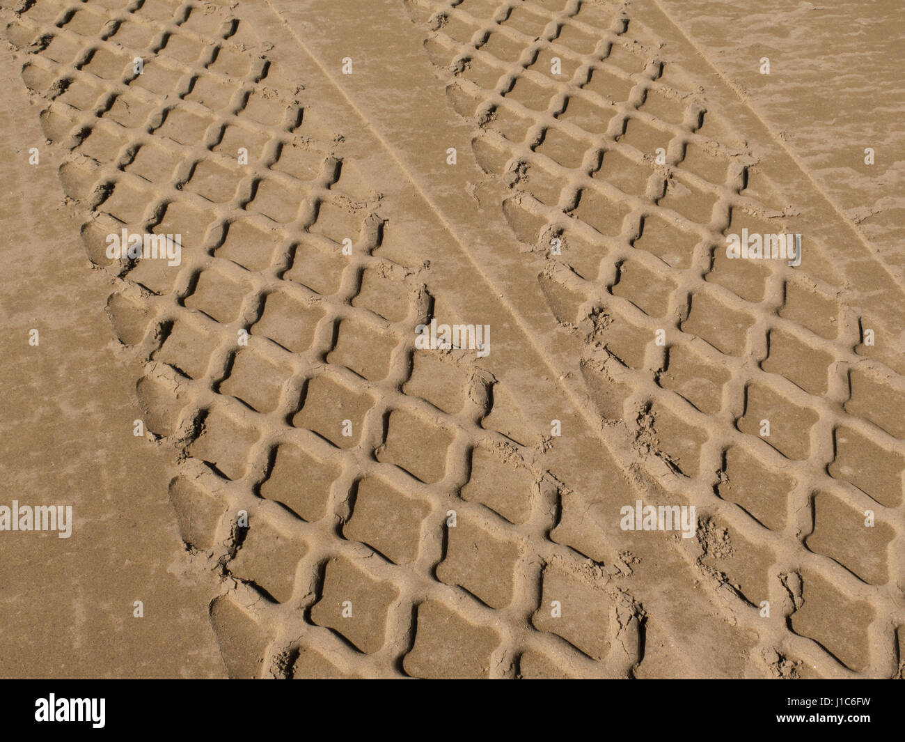 Tracks in sand by heavy road roller which compresses sand for asphalt ...